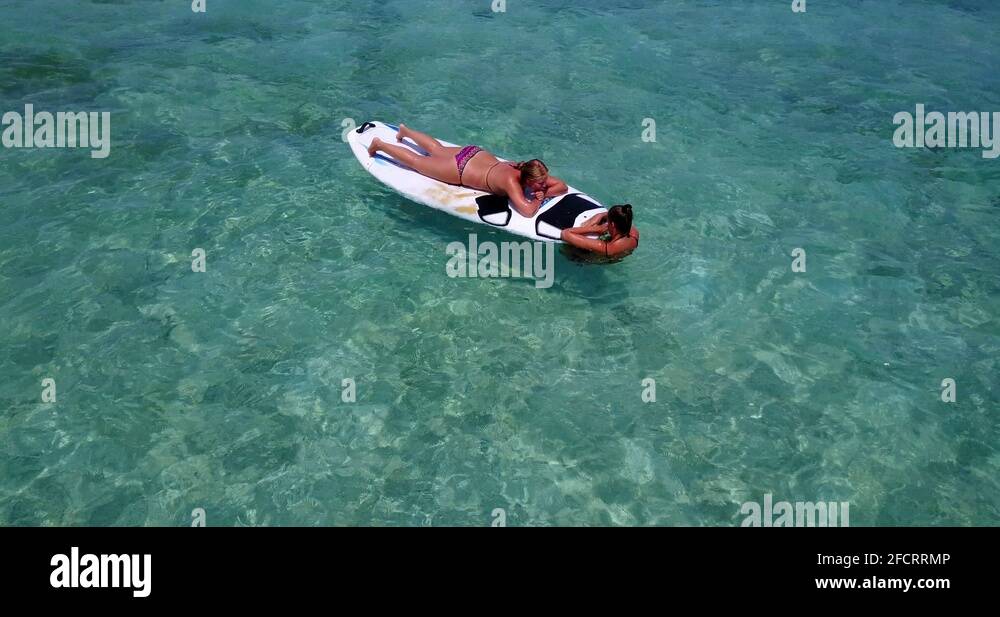 Woman laying on a surfboard sunbathing, people enjoying their vacation ...