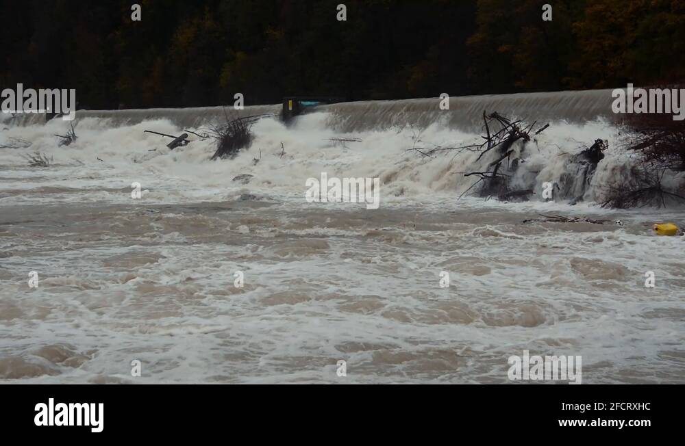 Garbage trash floats in circles in violent flood river over a small dam ...
