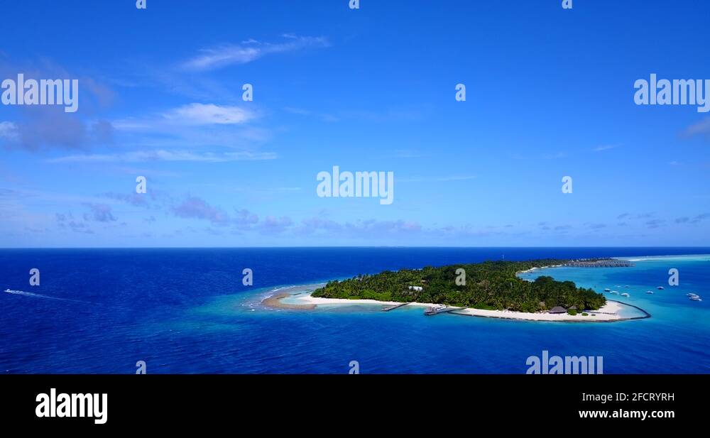Light blue sky and navy blue ocean surrounding stunning tropical island ...