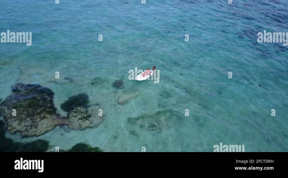 Woman in bikini tanning laying on a surfboard, girl in the ocean ...