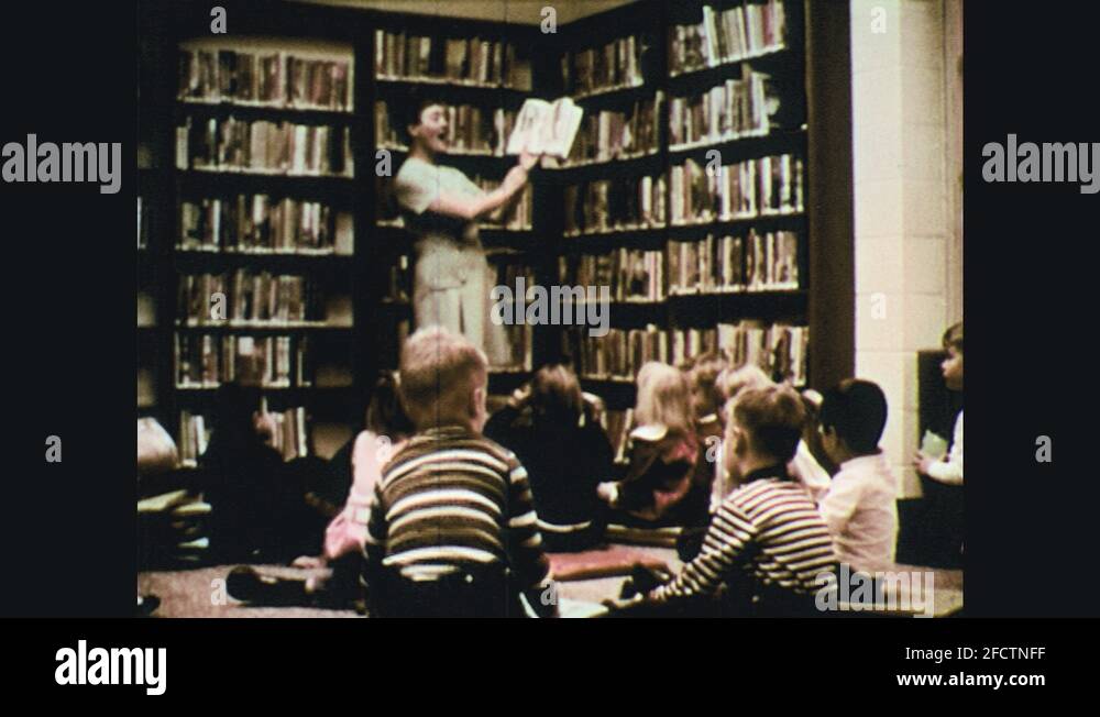 1970s: woman reading book aloud to children, children looking at a book ...
