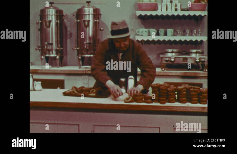 1960s: Man stacks doughnuts on counter. Boy grabs tray, transfer ...