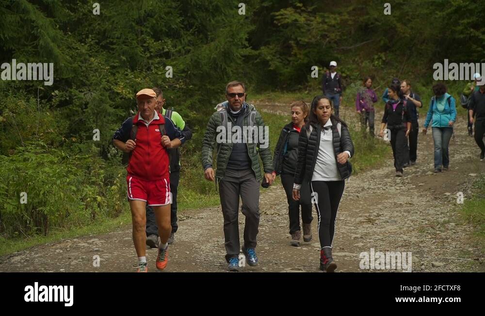 A large group of people walk together on a trail at Via Transylvania ...