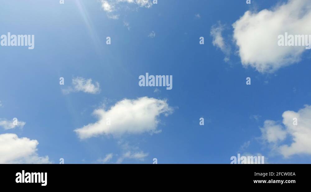 Static tripod shot of blue sky with some sporadic clouds and the sun ...