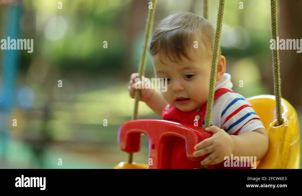 Contemplative baby boy in playground park swing thinking Stock Video ...
