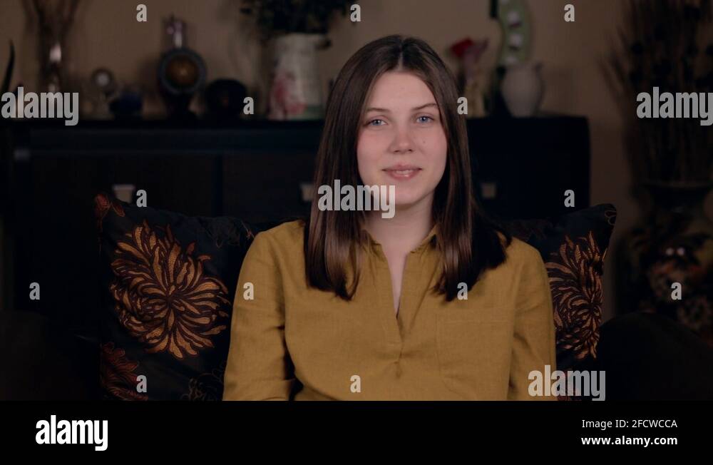 A young girl of Caucasian appearance sits in a chair laughing and ...