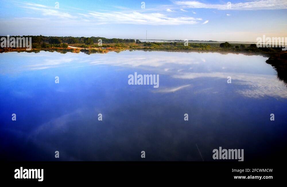 Low flying over a glassy water pond during a sunrise flight in Florida ...