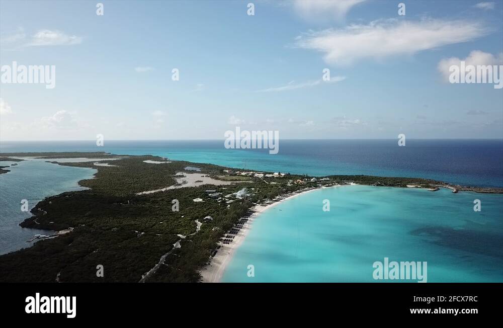Slow flight over a moon shaped Bahamian island beach from high done by ...