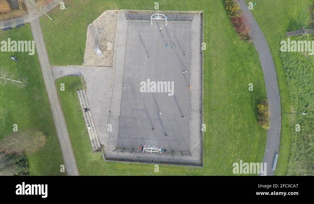 Top down aerial of children playing soccer on small concrete soccer ...