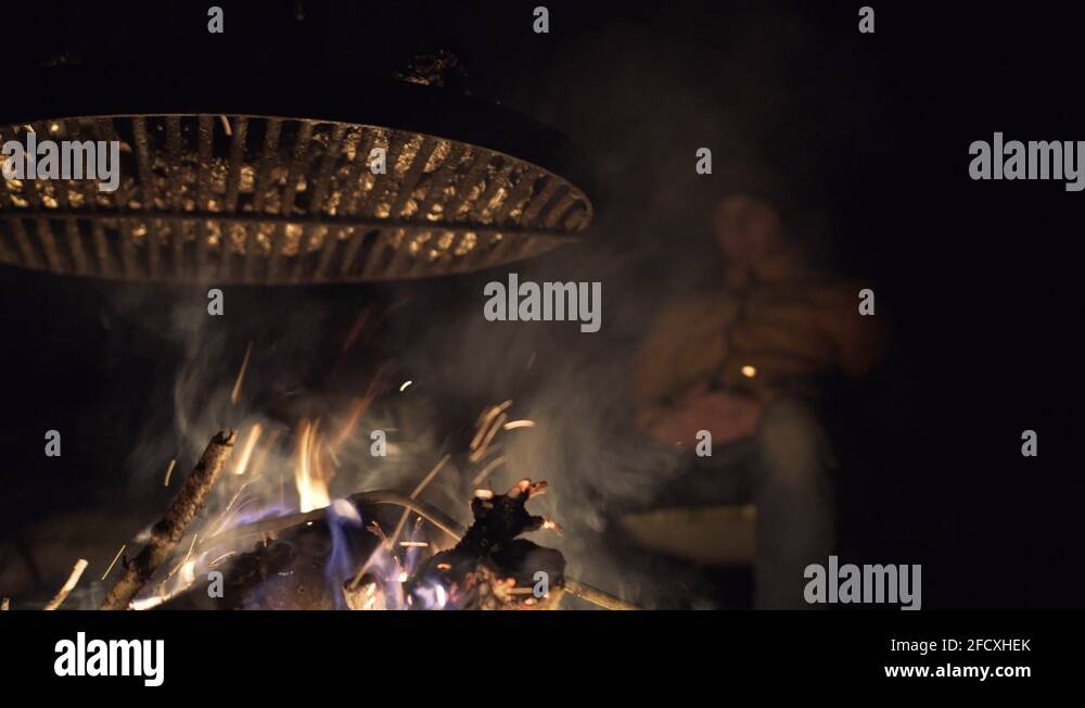 Adult Male Sitting Beside Campfire and Moving Grill. Low Angle And ...
