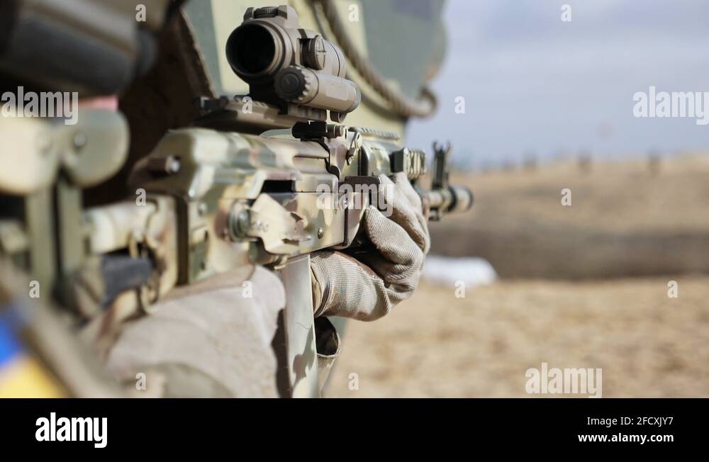 Man`s hand pulling trigger of assault gun with an optical sight in a ...