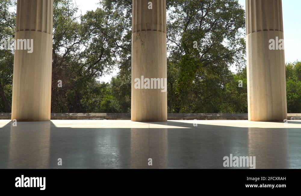 man walking out to greek pillars looks down and leans back, still low ...