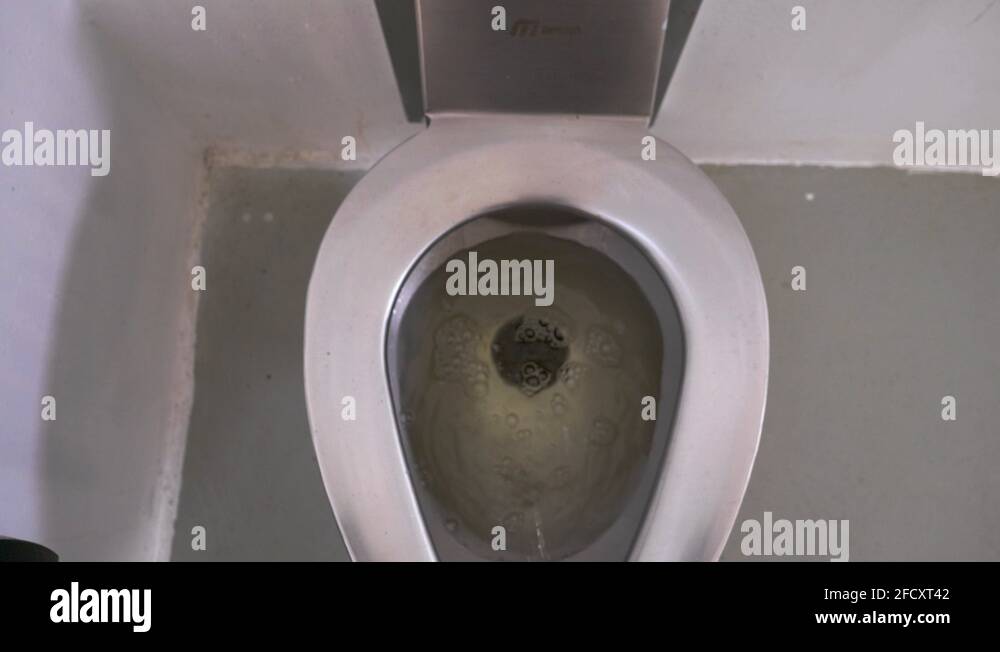 Male urinating in a public restroom. Stainless steel toilet. Handheld ...