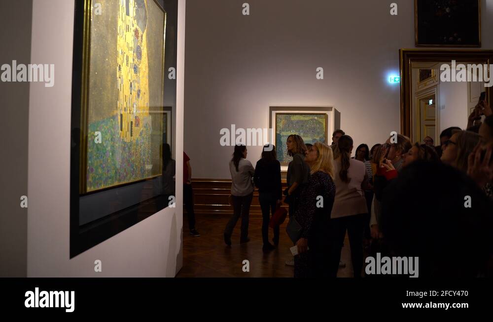 tourist looking at kiss by klimt inside museum, side view still shot ...