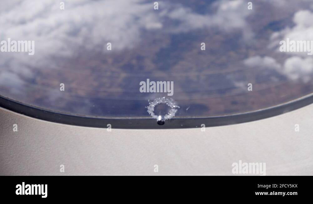 Frozen ring around plane`s fuselage window - clouds and landscape from ...