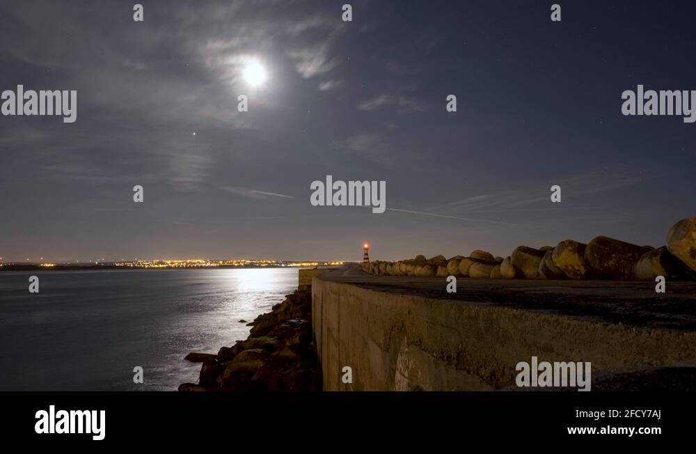 Bright moon illuminates the sea and a footbridge on which fishermen ...