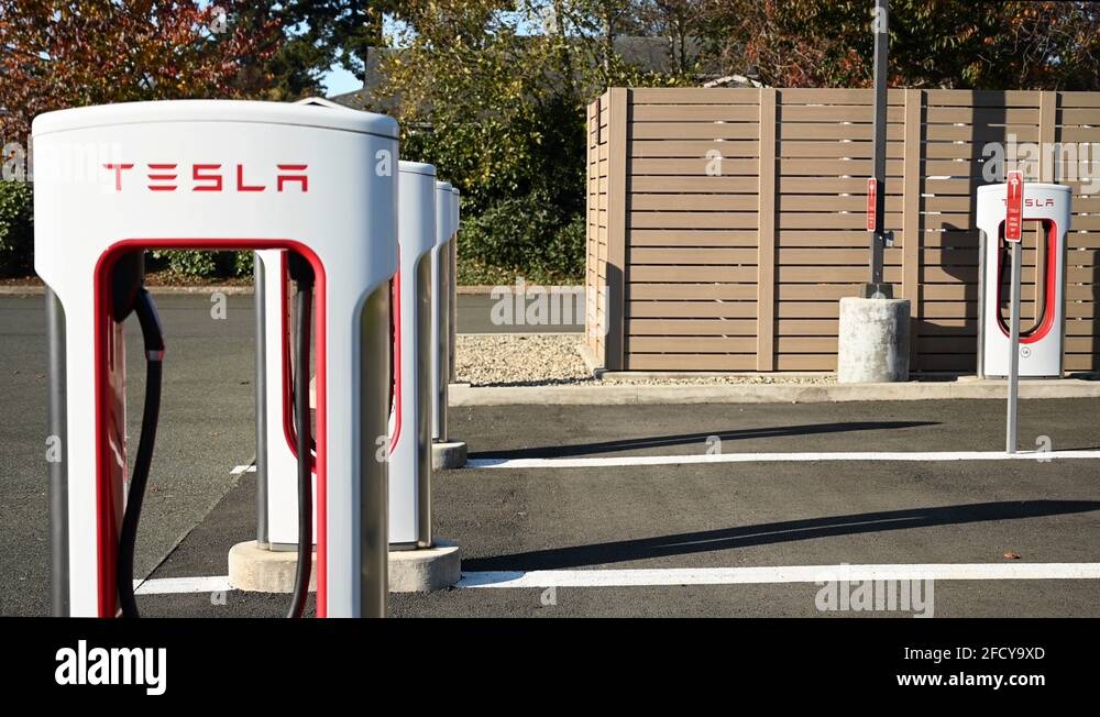 Tesla charging station in parking lot. Truck drives by in background ...