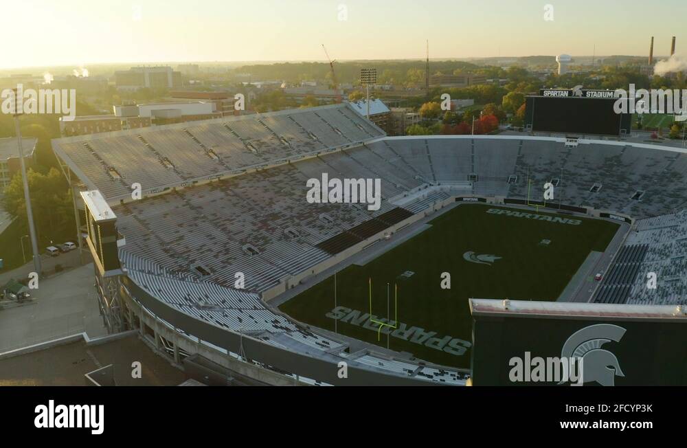 Aerial circling empty football stadium, warm sunrise in background ...