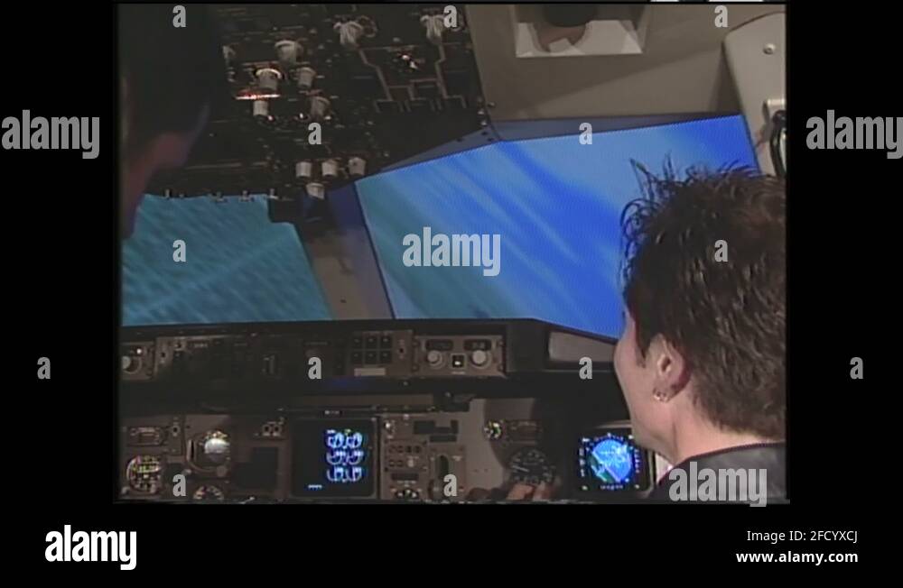 1990s: Man shows man how to fly airplane simulator. Two men have ...