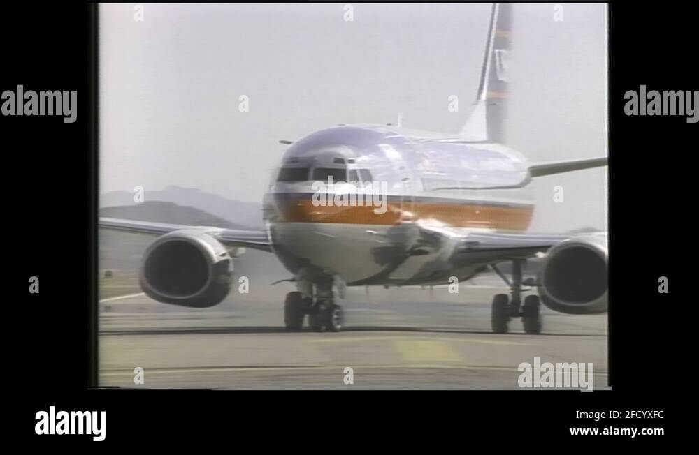 1990s: Commercial airplane on runway. Airplane takes off as plane comes ...