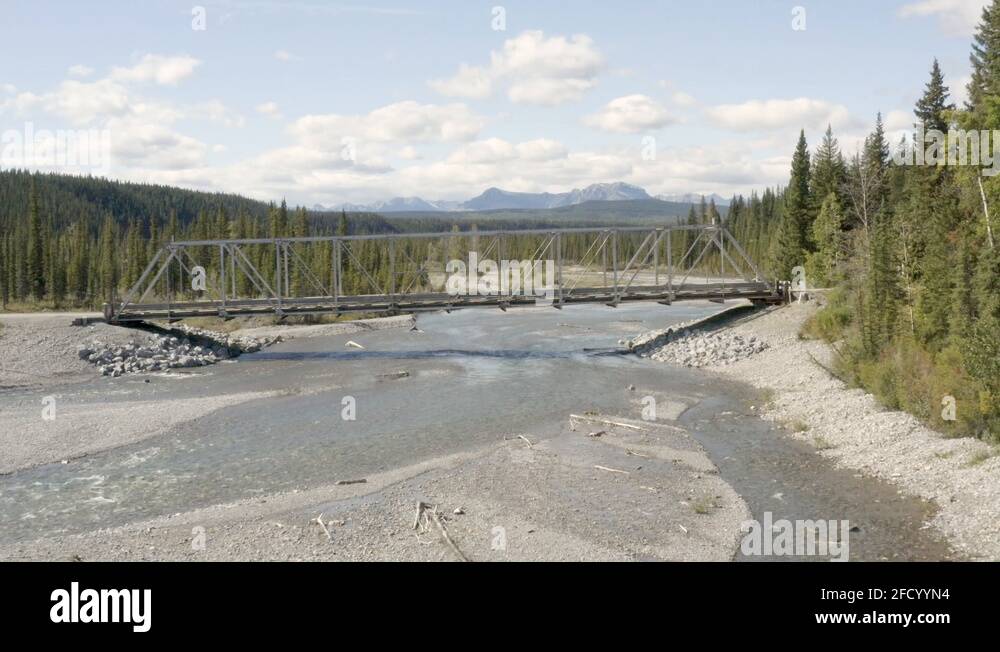Flying over an iron bridge a red car crossing the bridge from left to ...