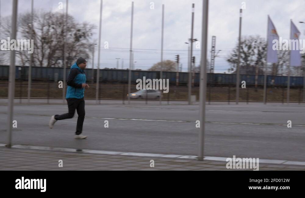 A handheld shot tracking a man running down a road in Poland, outside a ...