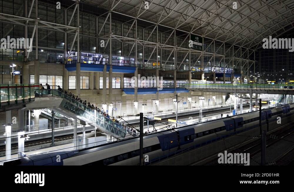 Passengers disembark the high speed train and go up the escalator of ...