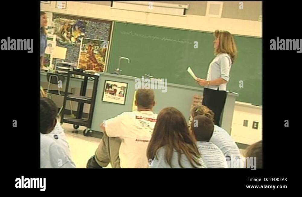 1990s: Girl approaches teacher in classroom. Girl speaks to class near ...