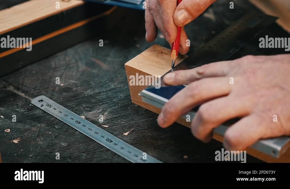 Carpentry industry - a man woodworker making marks for cutting on the ...