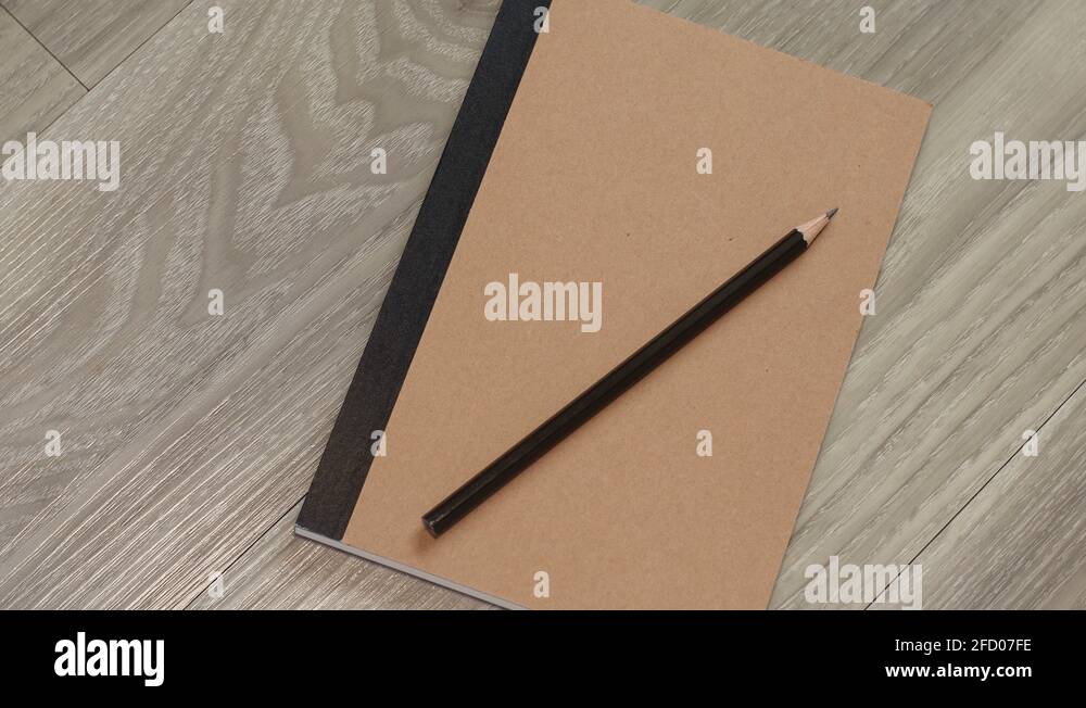 A brown notebook and black pencil lying on the floor, drawing and Stock ...