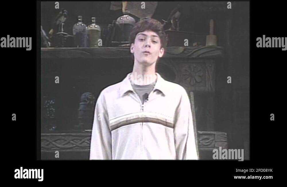 1990s: Young man stands on stage on medieval castle set, talking. Young ...