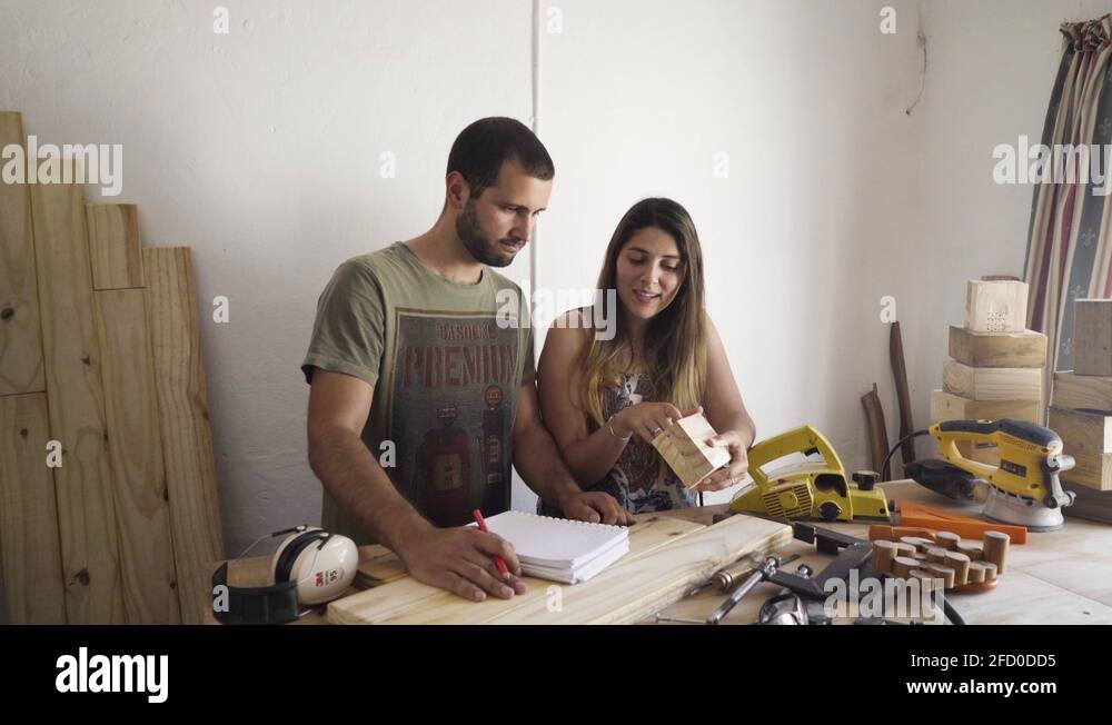 Two people at a carpenter's desk workbench draw up plan for a ...