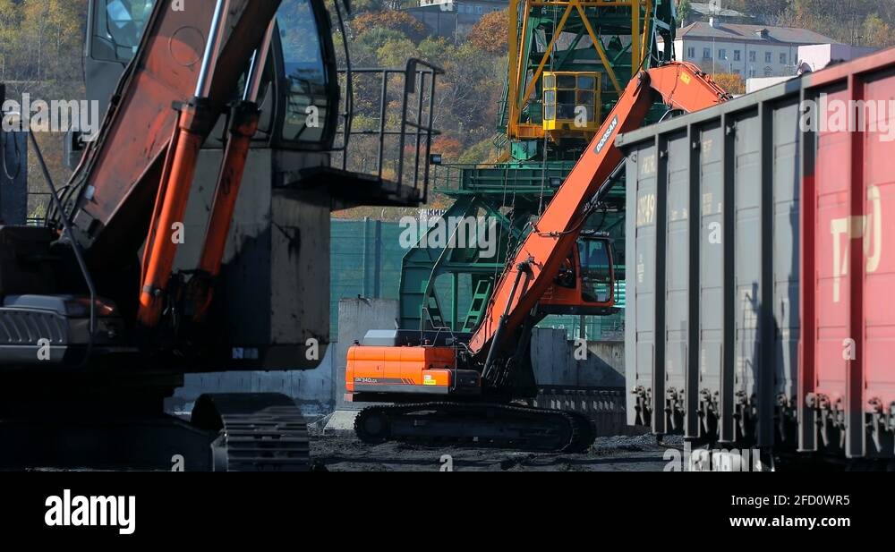 A loading and unloading crane unloads coal from railway wagons Stock ...