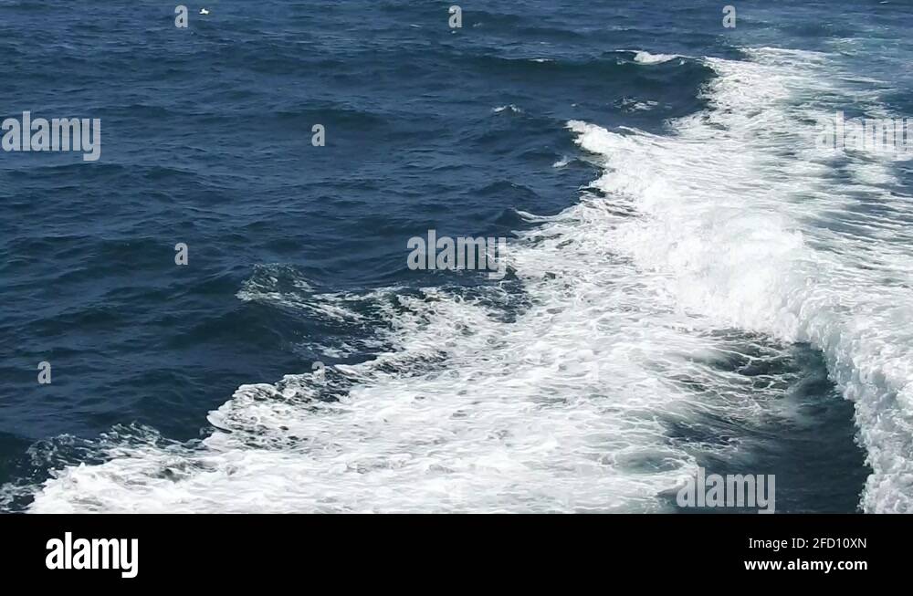 Ocean waves and splash from the side of a traveling cruise ship.Blue ...