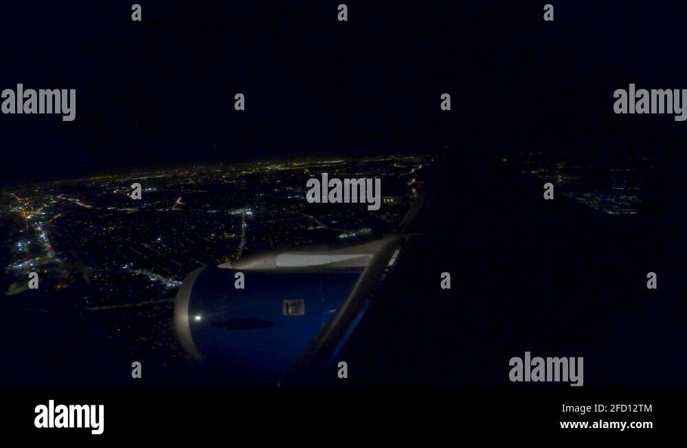 A shot for the window of an airplane flying over a city at night Stock ...