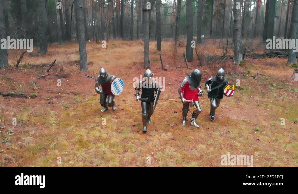 Four men knightes running in the row in the forest in full armour ...