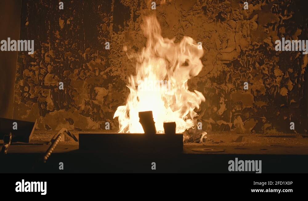 Forge fire in furnace. Blacksmith tempers a steel product in a stove ...