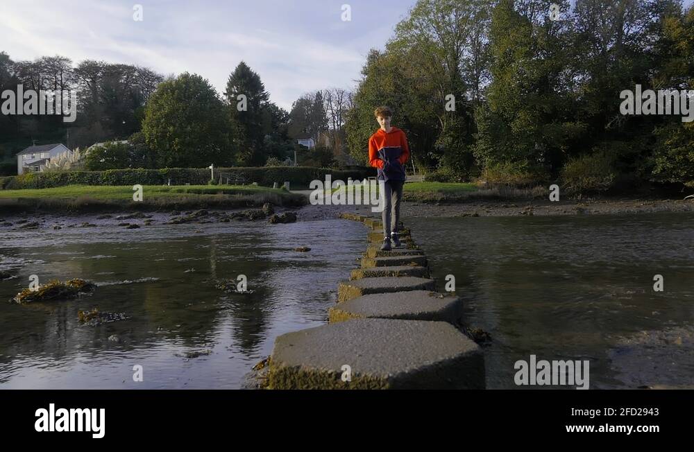 Boy Walking On A Stone Walkway In UK To Cross A Shallow River - Wide ...