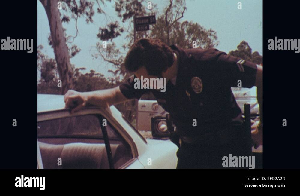 1970s: Police officer standing next to car talks to passenger in back ...