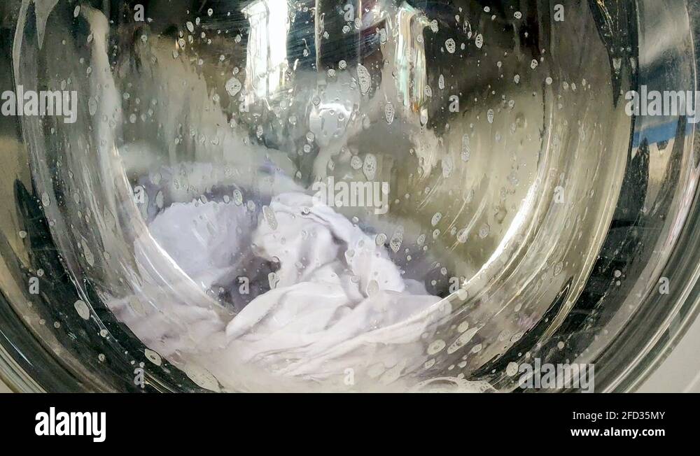 Washing Clothes. Laundromat Clothes tumble washing in machine close up ...