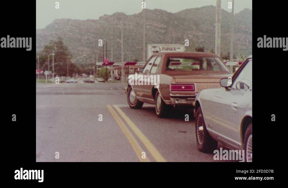 1970s: Car drives around gate at railway crossing. Train rolls down ...