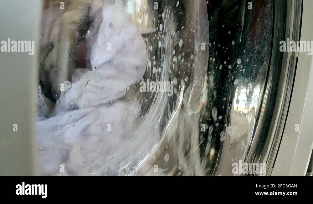 Washing Clothes. Laundromat Clothes tumble washing in machine close up ...