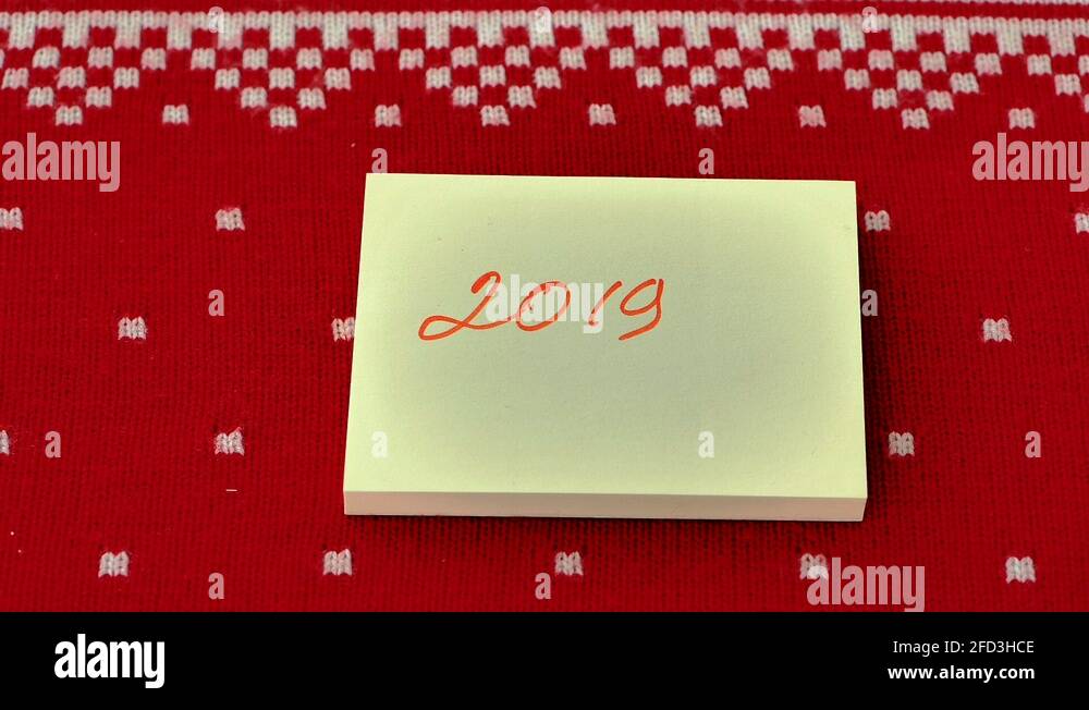 Handing Post-It note with change of year against red design background ...