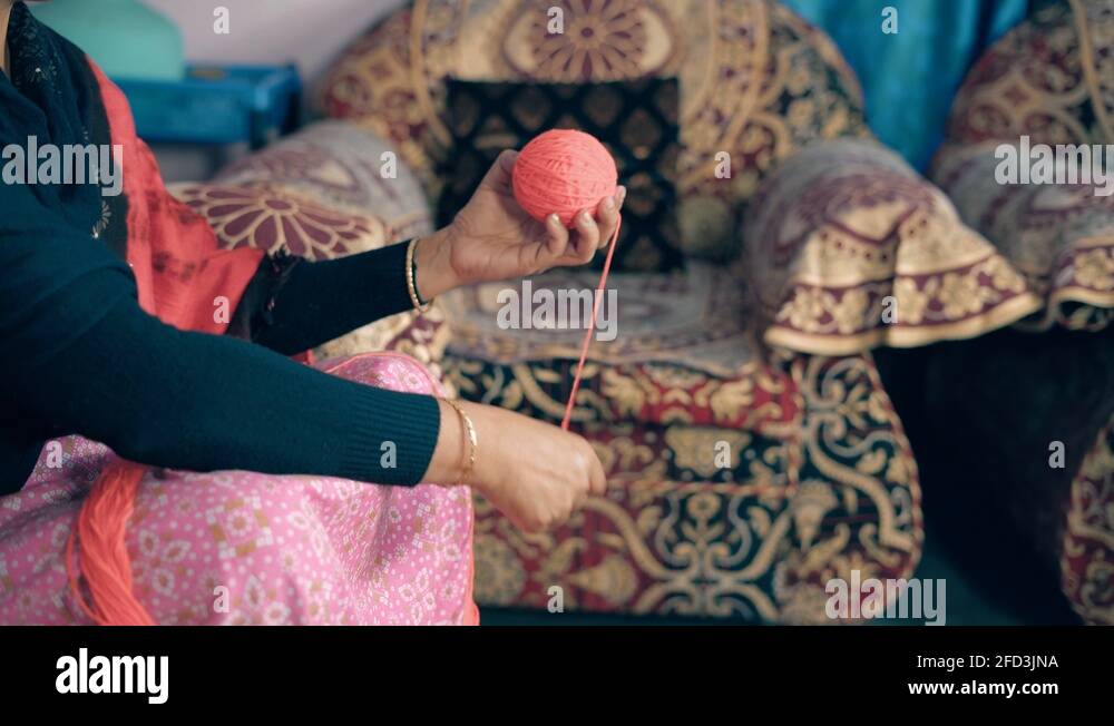 Traditional Indian woman roll the red thread into a ball and preparing ...