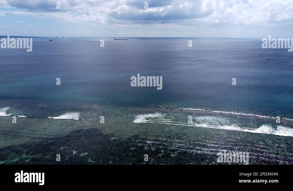Ocean waves breaking near the shore, with coral reefs and container ...