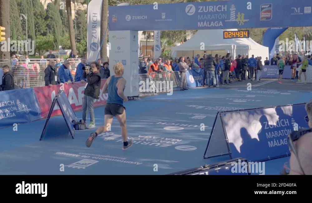 Runner in marathon crosses the finish line, clock showing under three ...