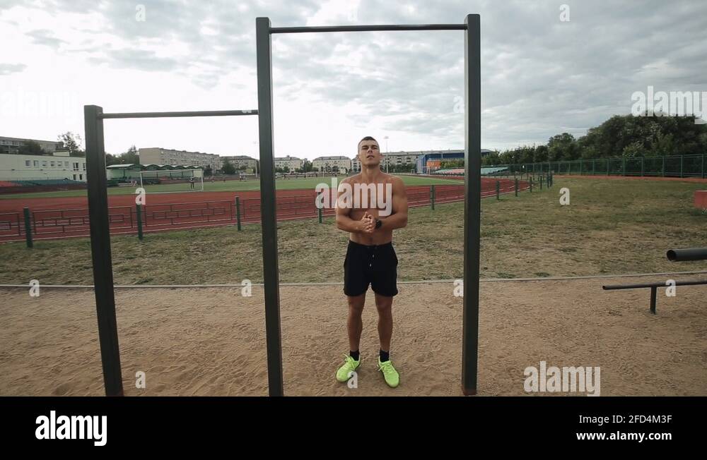Fit young man doing hanging leg raises exercise on horizontal bar in ...