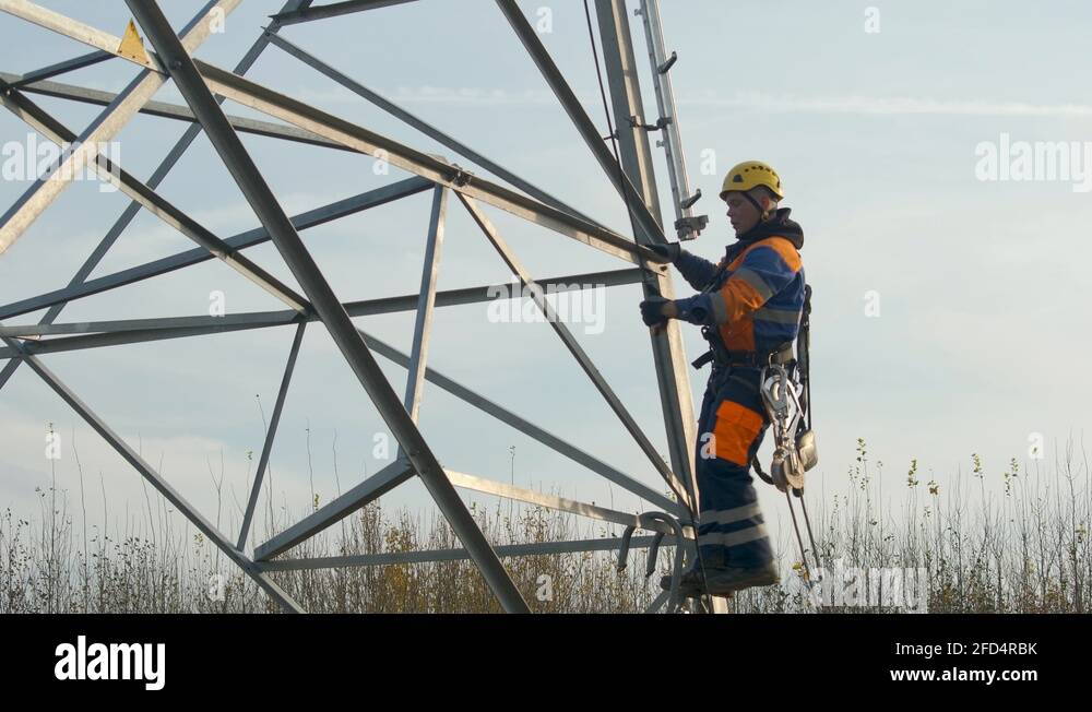 Electrical engineer with dangerous job climbs up pylon, wearing safety ...