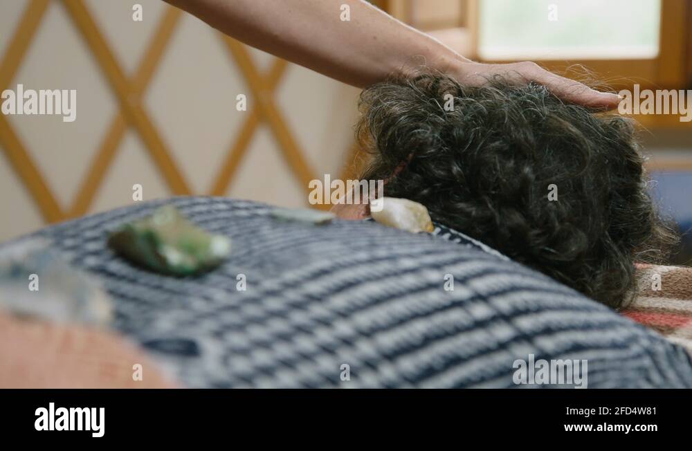 Healing hands apply pressure to a clients back and head during reiki ...