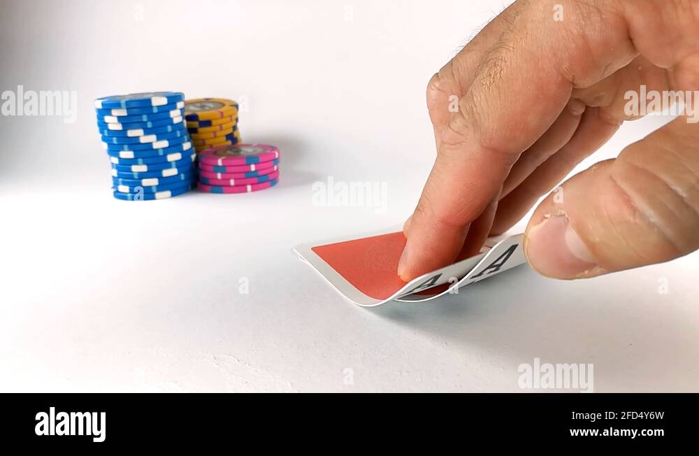 Male hand revealing two playing cards laying face down on a white table ...